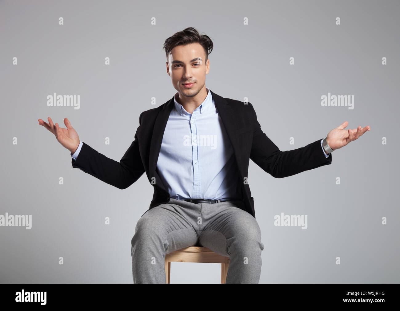 handsome seated businessman making a welcoming hand gesture on light ...