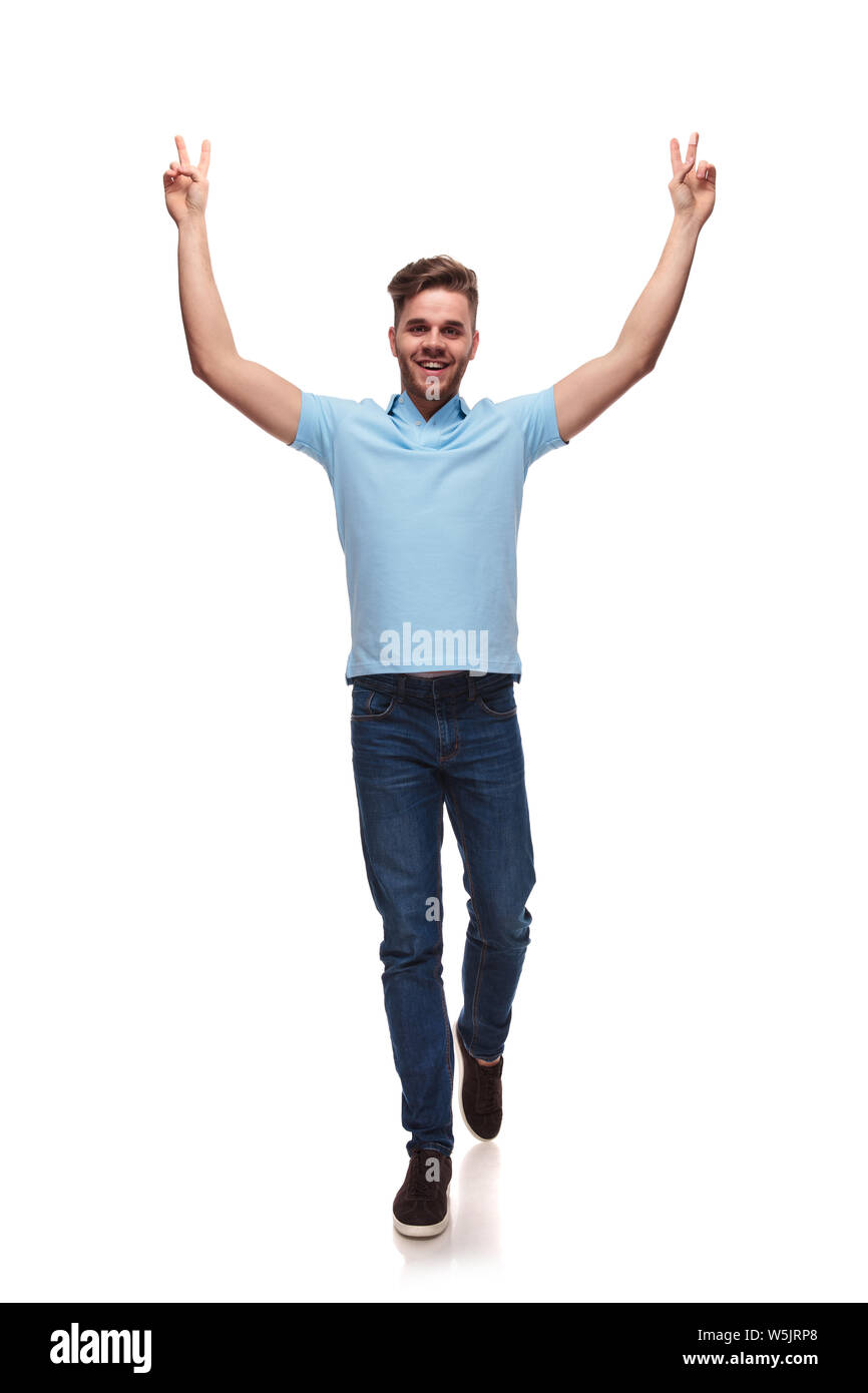 young casual man steps forward on white background while celebrating ...