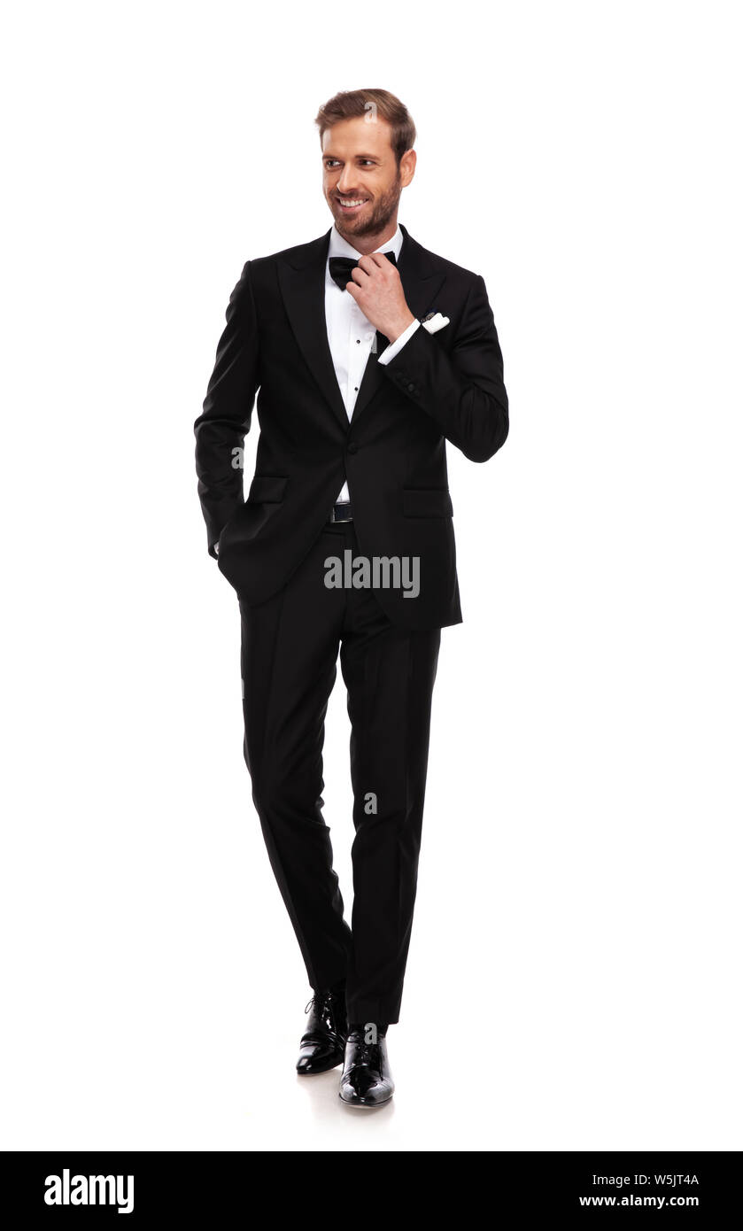curious businessman in black suit stands with hand in pocket on white ...