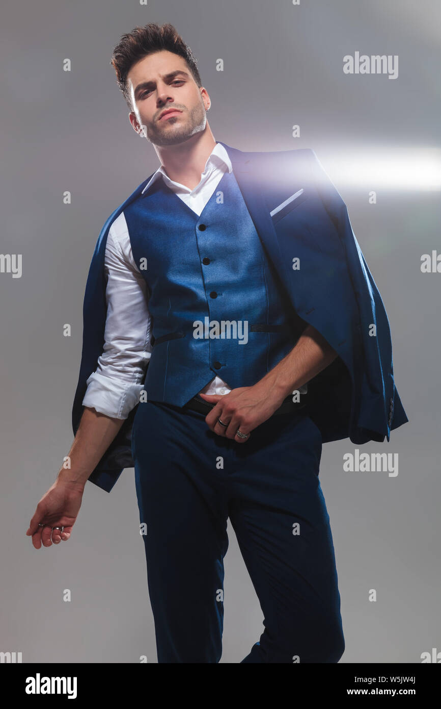 portrait of proud elegant man posing with suit on shoulders while ...