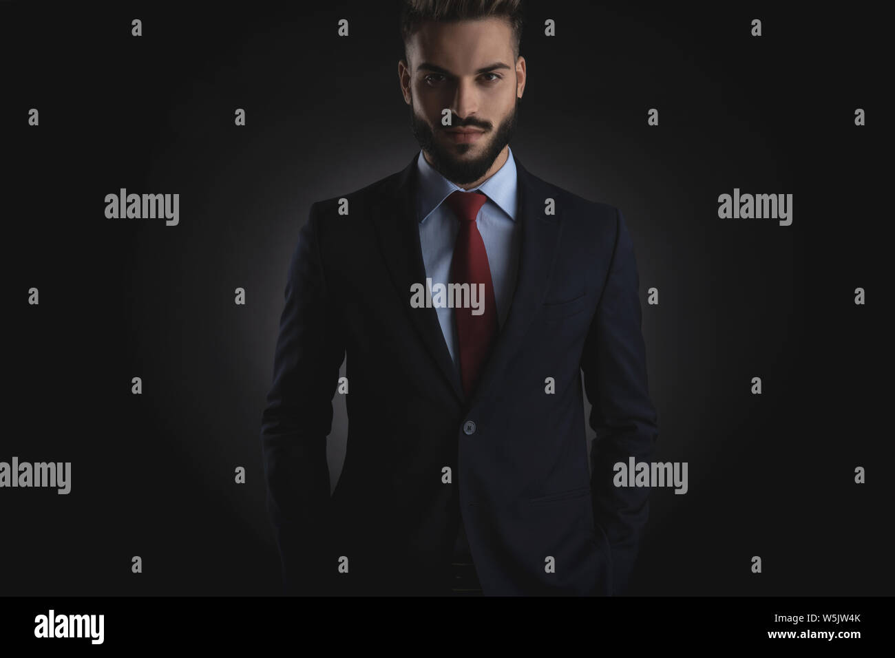 portrait of relaxed smart casual man standing with hands in pockets on ...