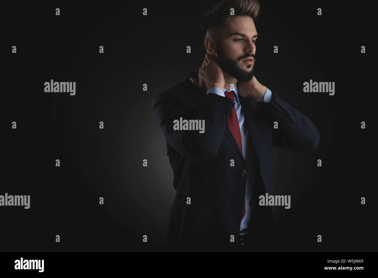 portrait of businessman in navy suit holding back of neck looking down ...