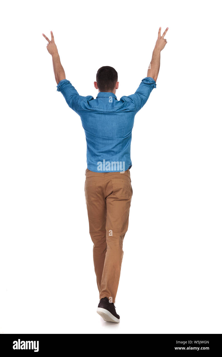 rear view of celebrating casual man walking on white background and ...