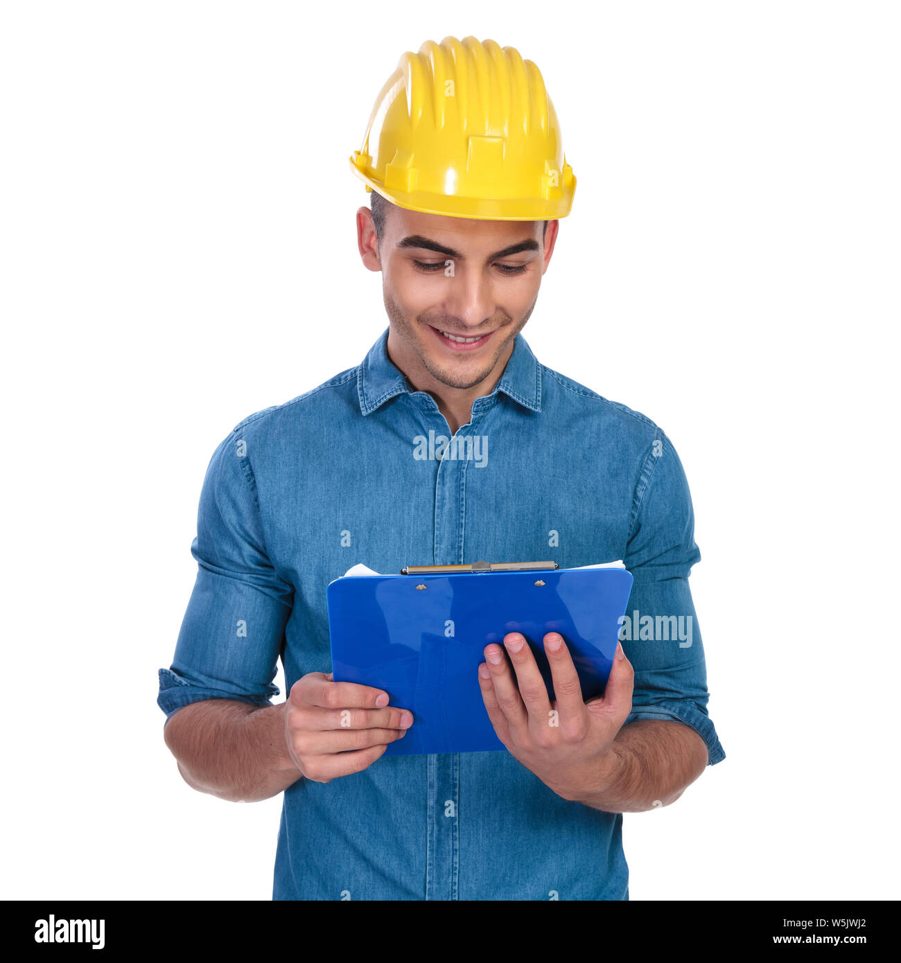 portrait of young engineer holding clipboard and reading while standing ...