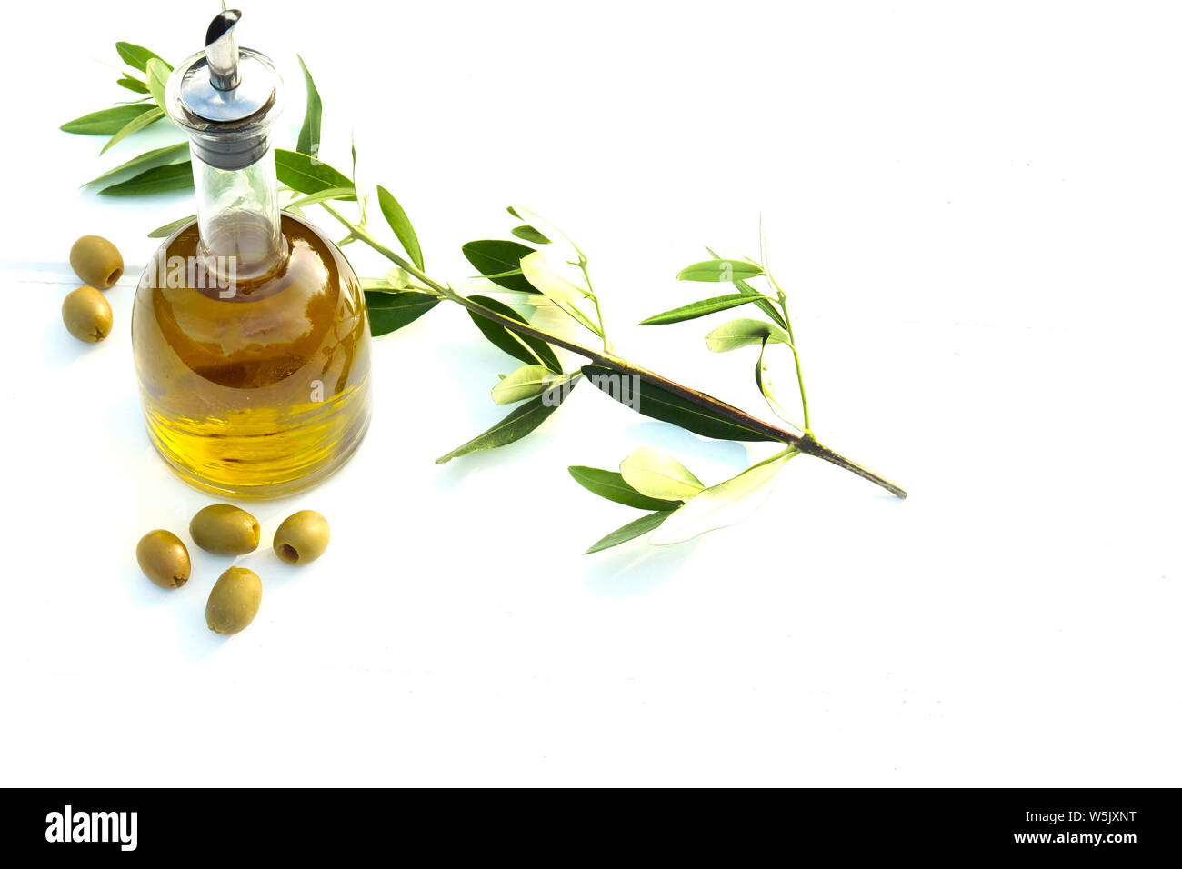 Olive oil in a glass pouring bottle, scattered around the bottom of the ...