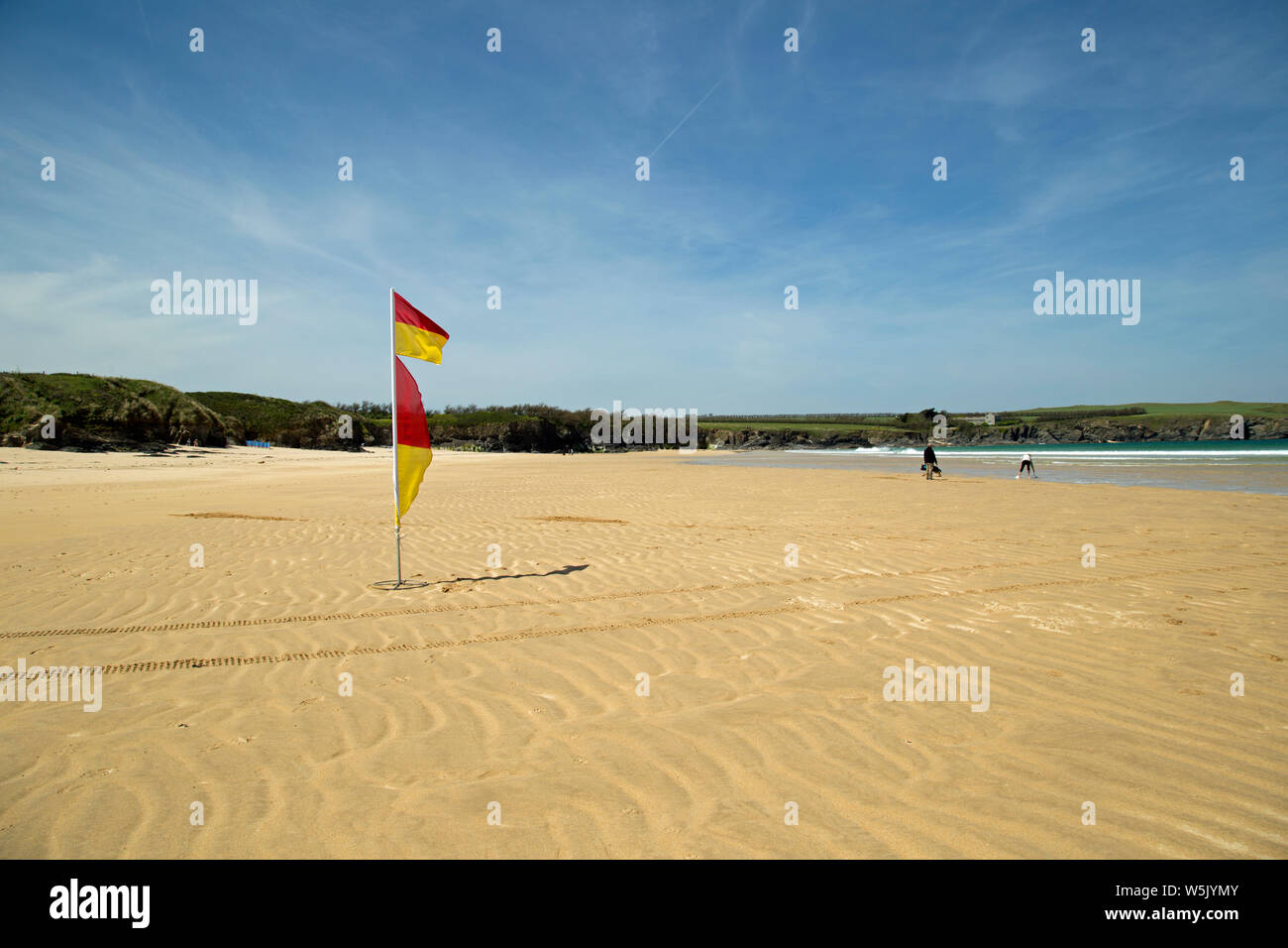 Red and yellow flags flying on a sunny day at a sandy cornish beach ...