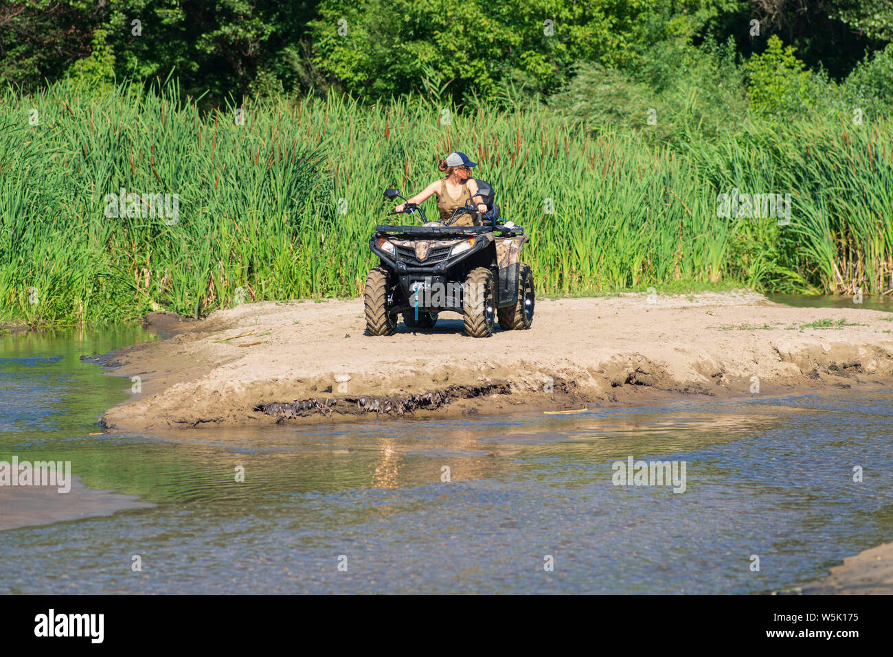 A girl on a Quad bike riding on the beach. A happy woman riding a quad ...