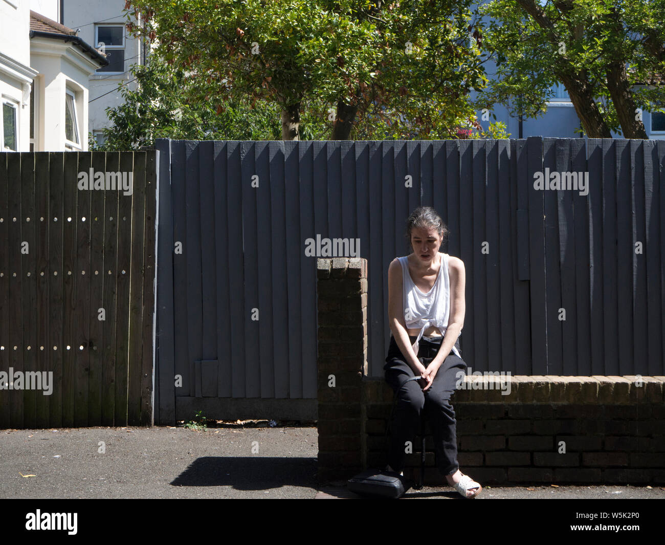 woman sitting alone on wall Stock Photo - Alamy