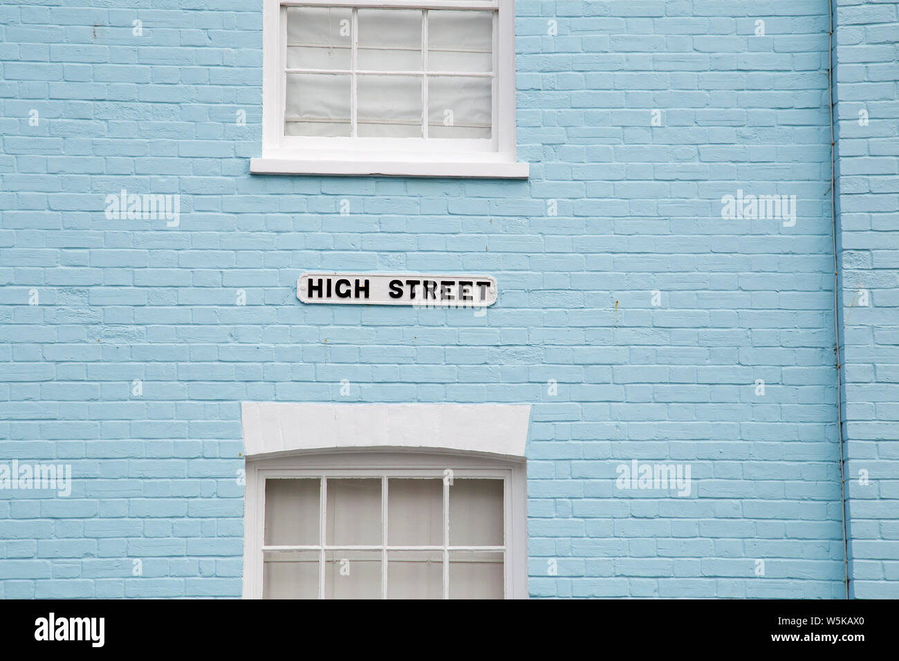 A "High Street" sign between two old style white painted sash windows ...