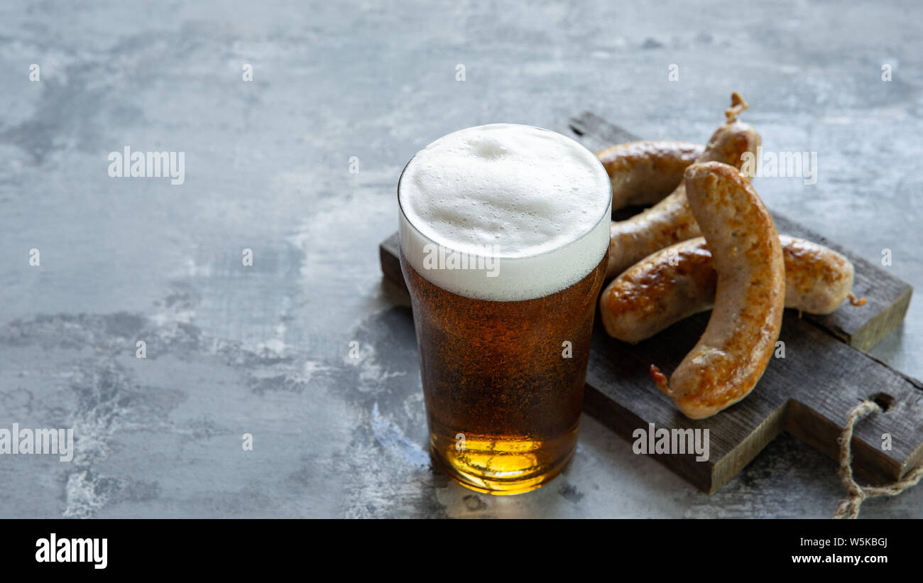 Glass of beer with foam on top on white stone background. Cold alcohol ...