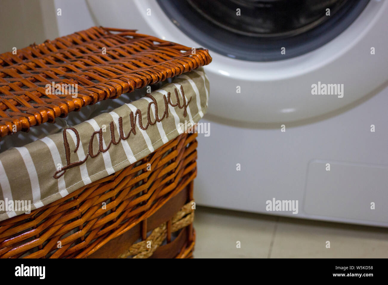 Laundry basket in front of a washing machine, with copy space on the ...