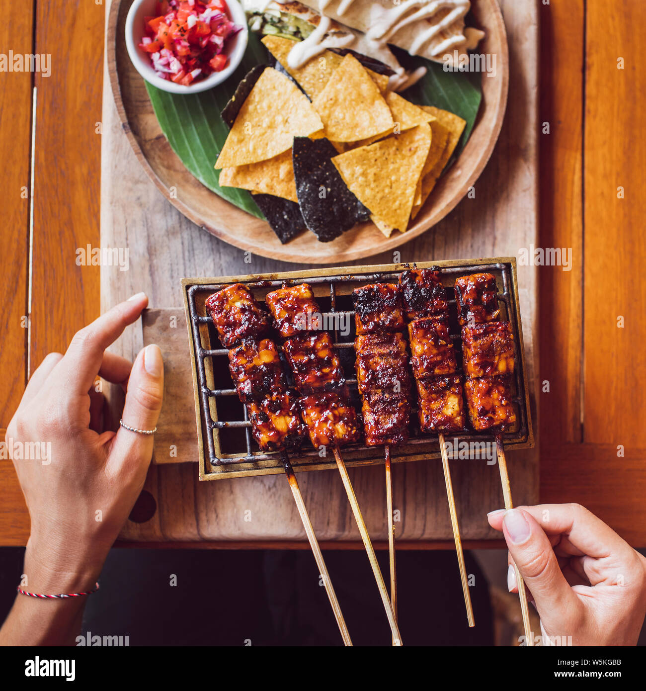 Woman is holding traditional indonesian grilled skewers of tempe ...