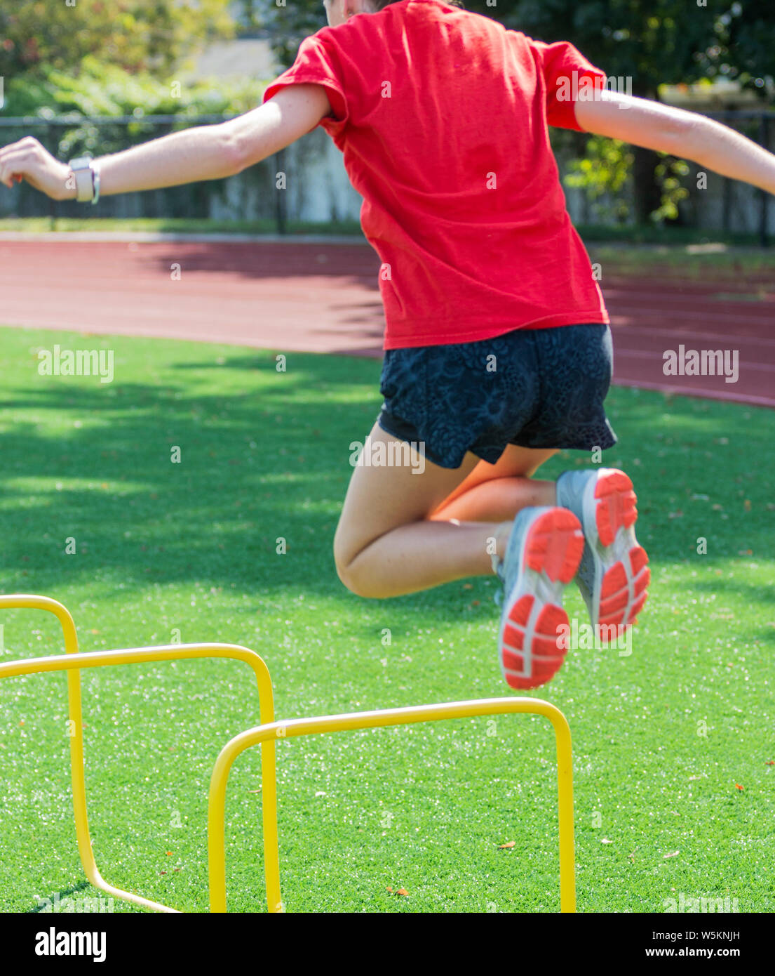 A high school teenage girl is jumping over two foot high yellow mini ...