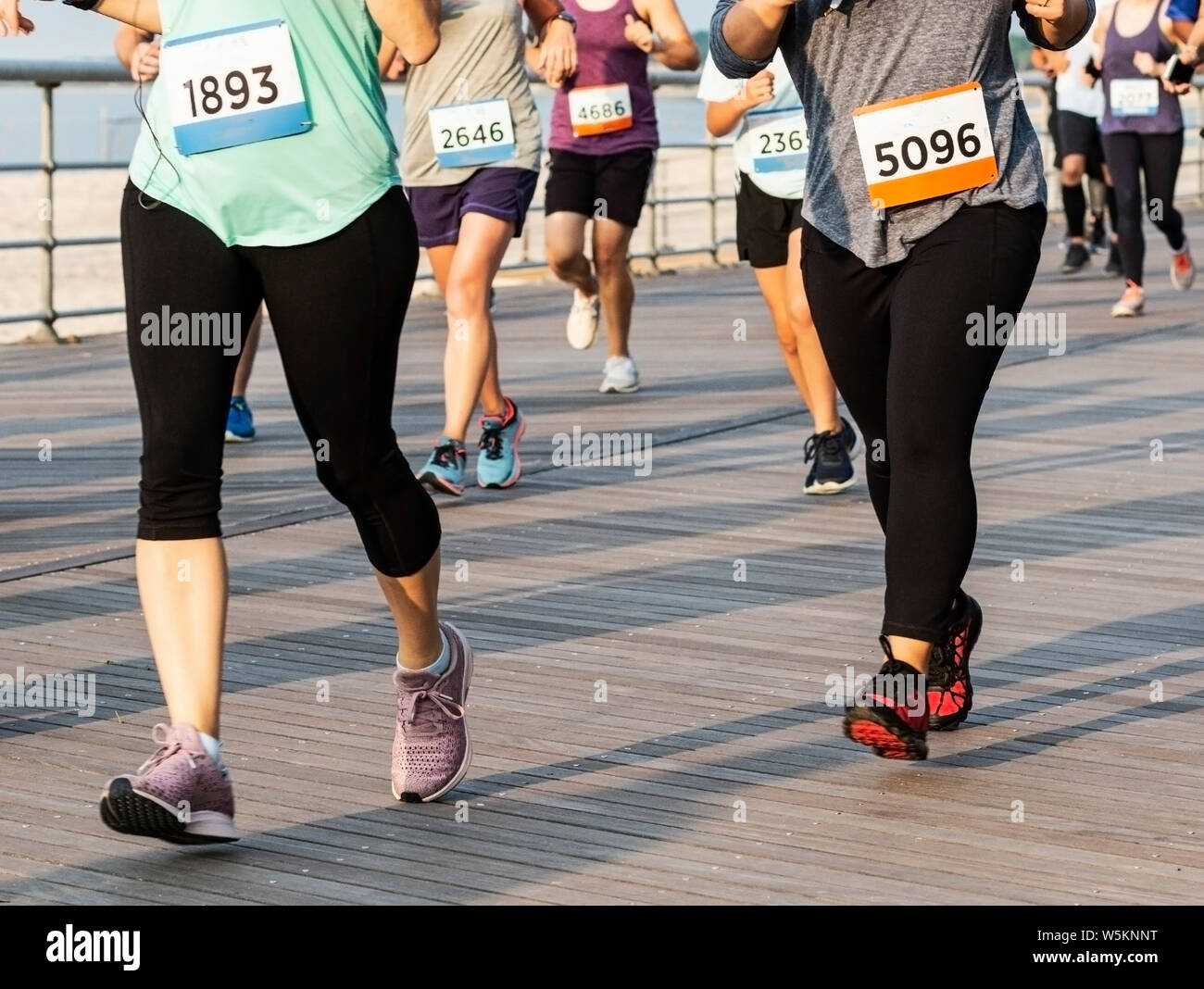 Many runners are running a race on a boardwalk by the beach shot from ...