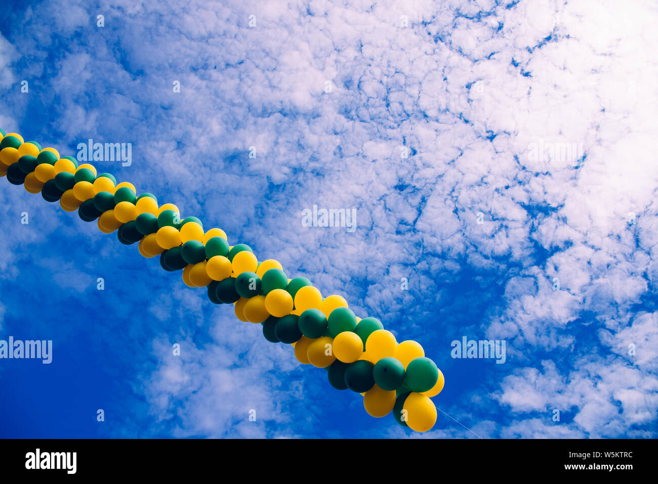 Row of colorful balloons crossing the blue sky with clouds, background ...