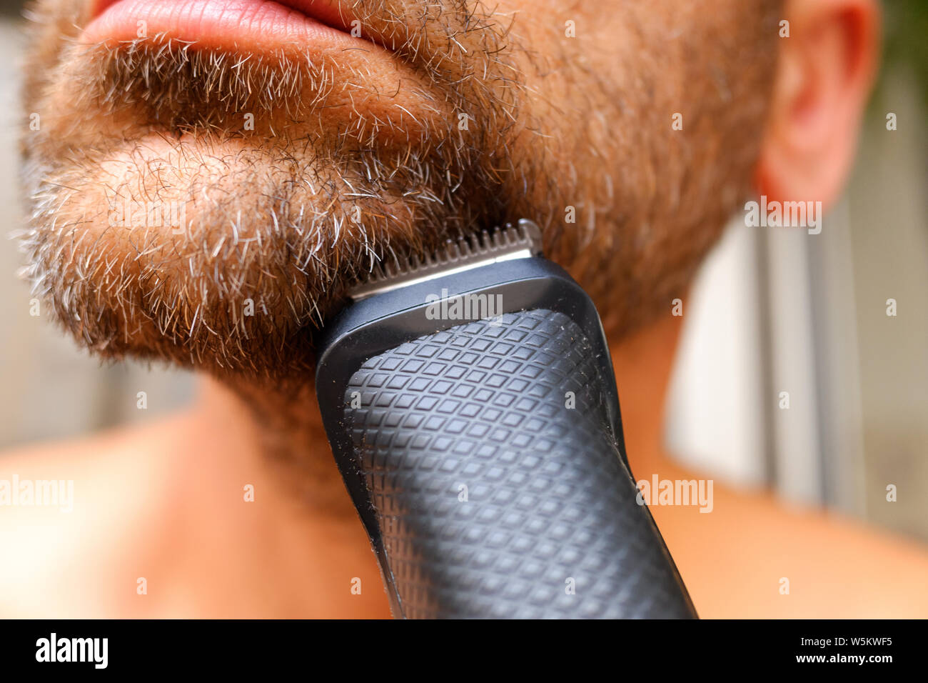 A man shaves his beard using an electric razor Stock Photo - Alamy