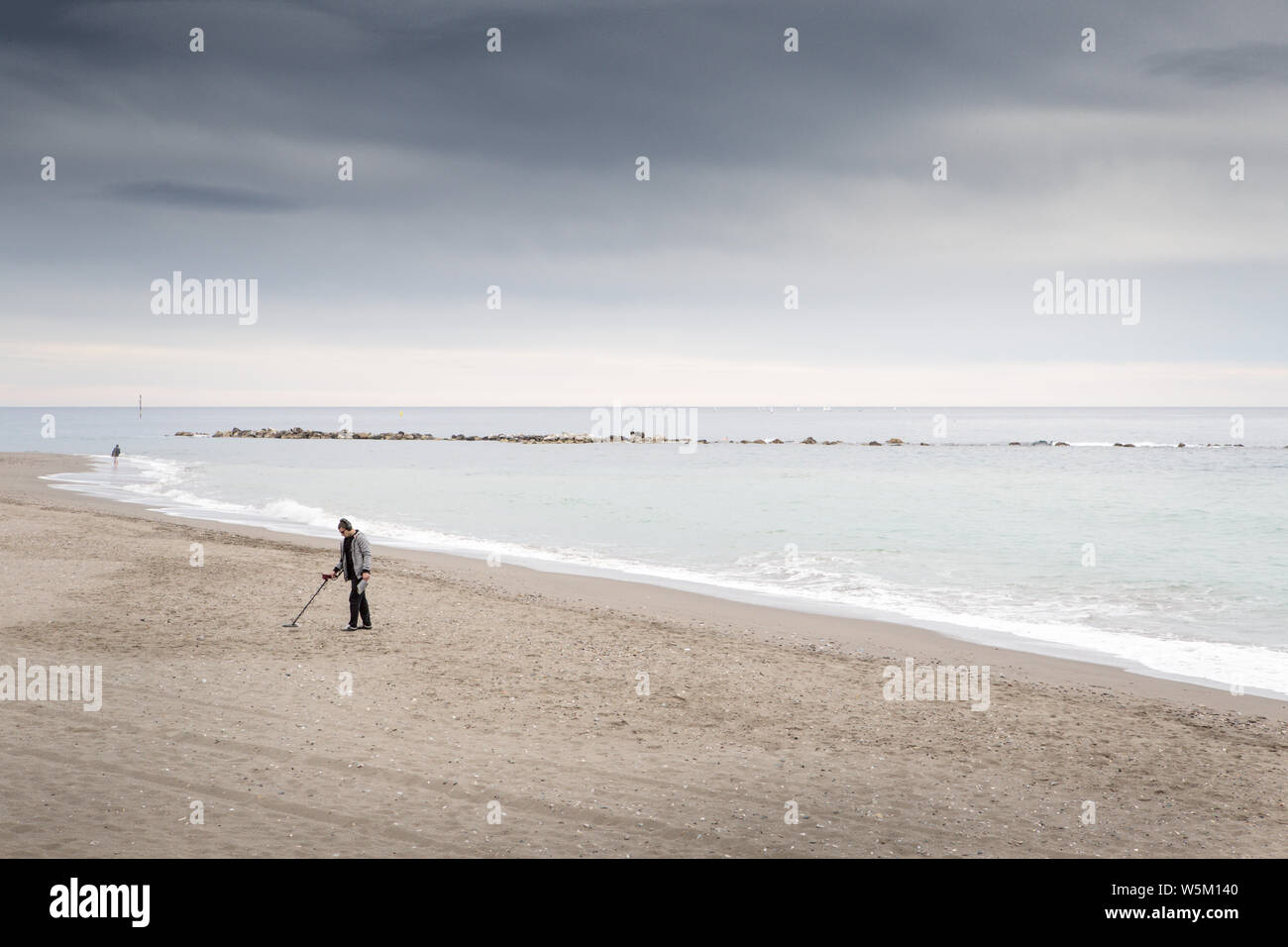 landscape shot of man scanning the beach with a metal detector Stock ...