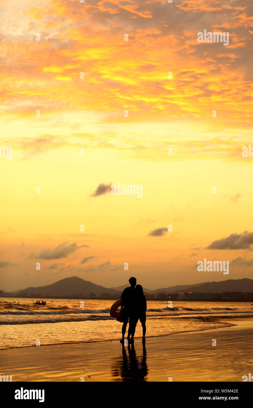 People enjoy leisure time amid sunset glow by the sea in Sanya city ...