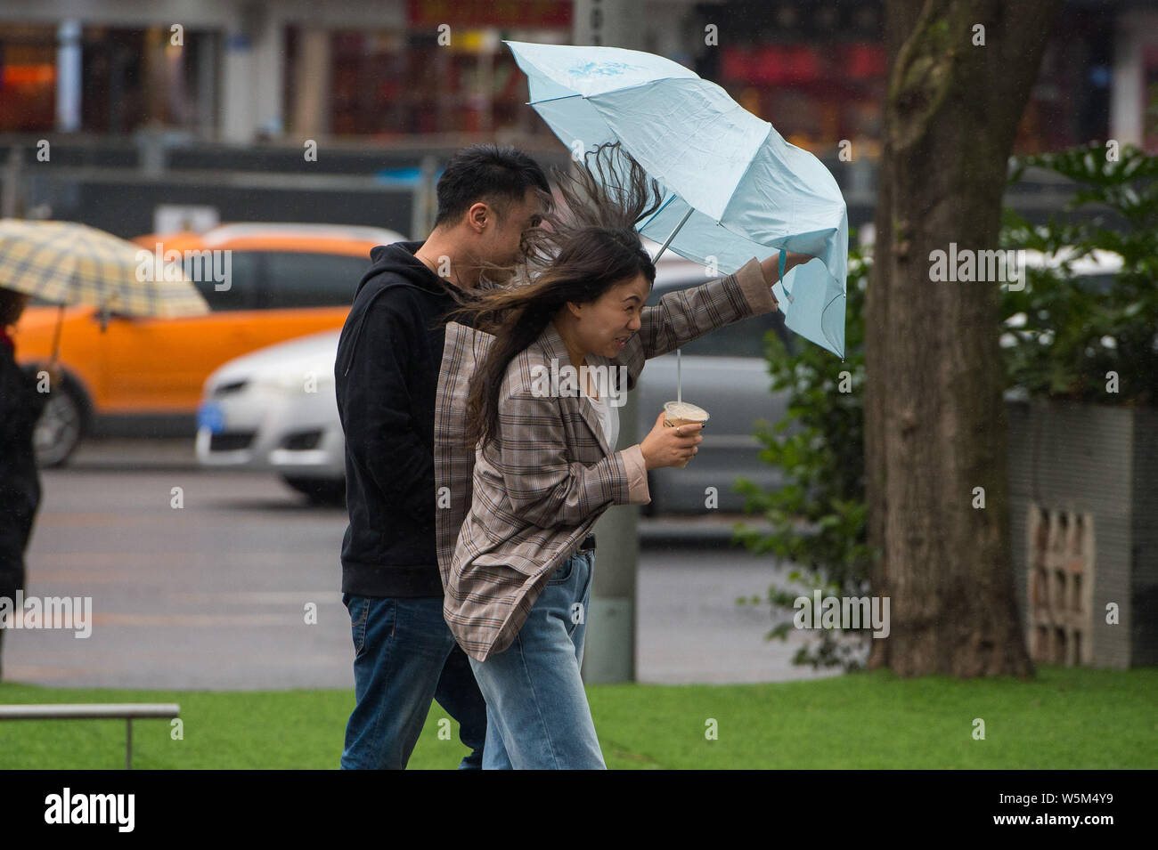 High wind breaks an umbrella and tumbles people's hair as wind and ...