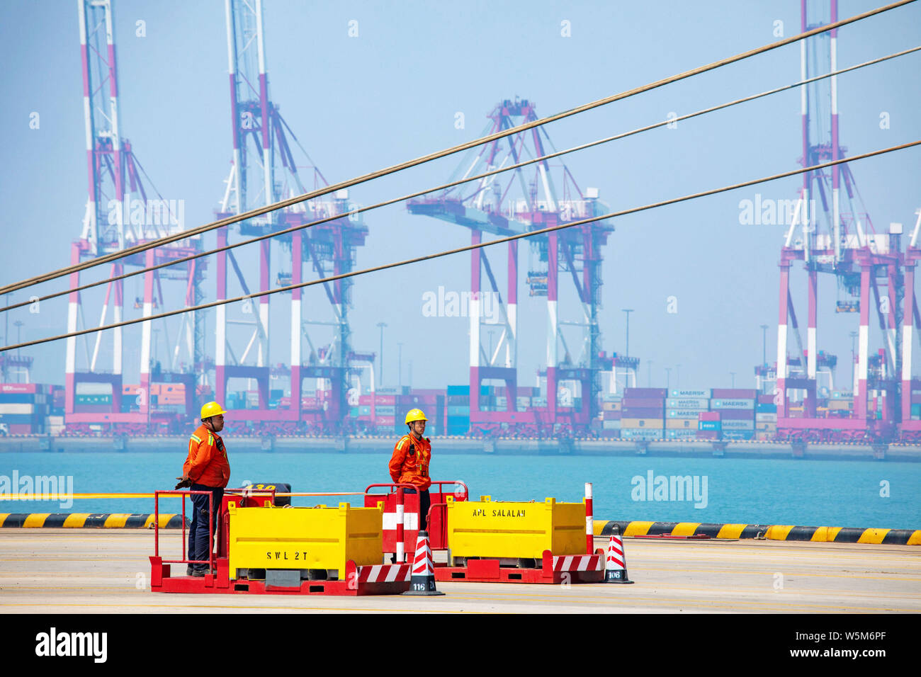 Chinese workers labor at the fully automated container terminal at the Port of Qingdao in ...