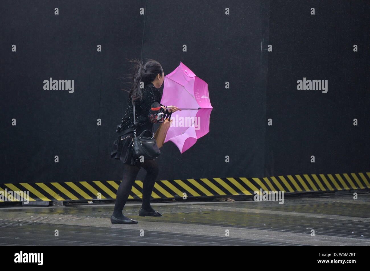 High wind breaks an umbrella and tumbles a woman's hair as wind and ...