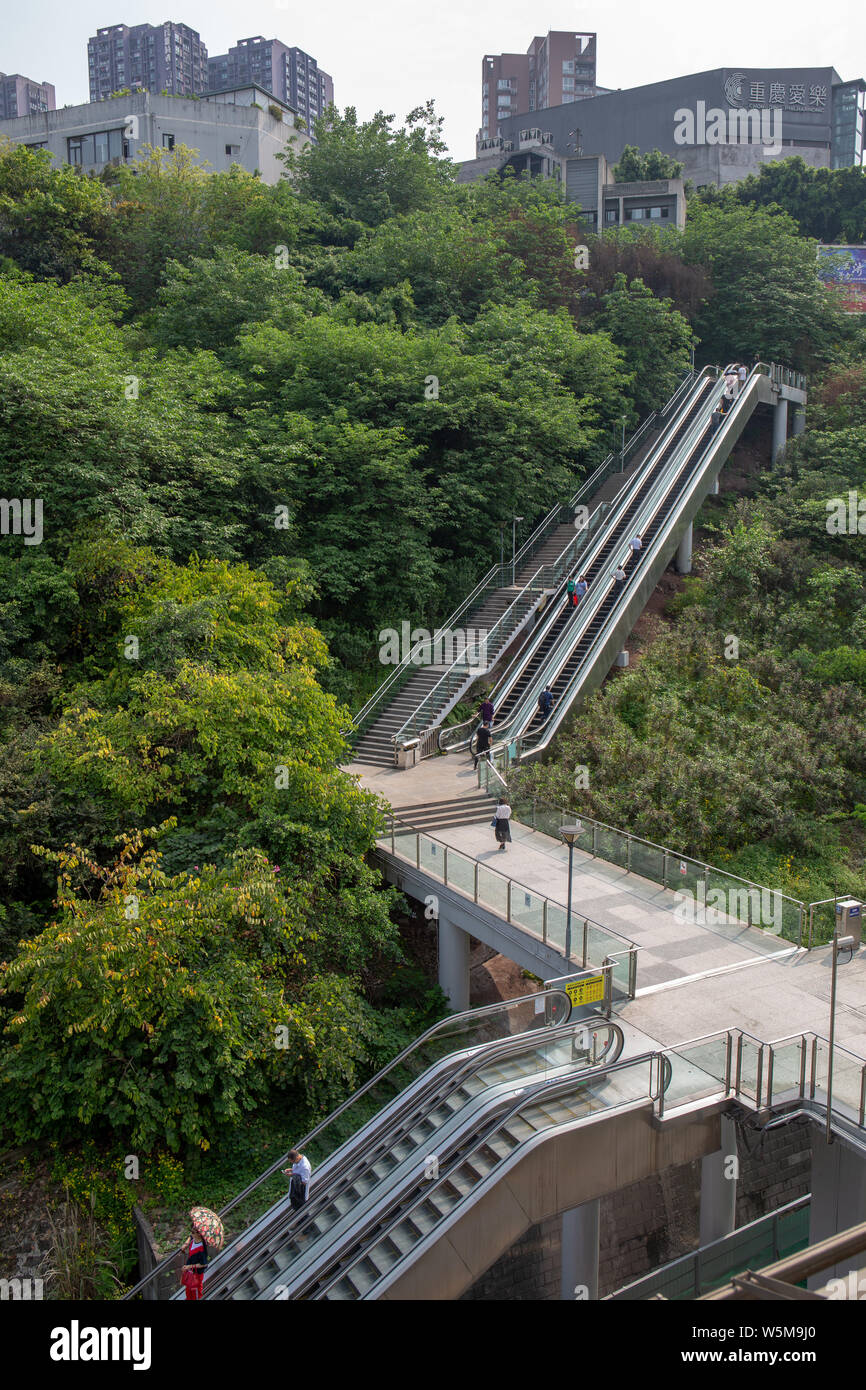 Local residents take the newly-built escalators to reach the top of a ...