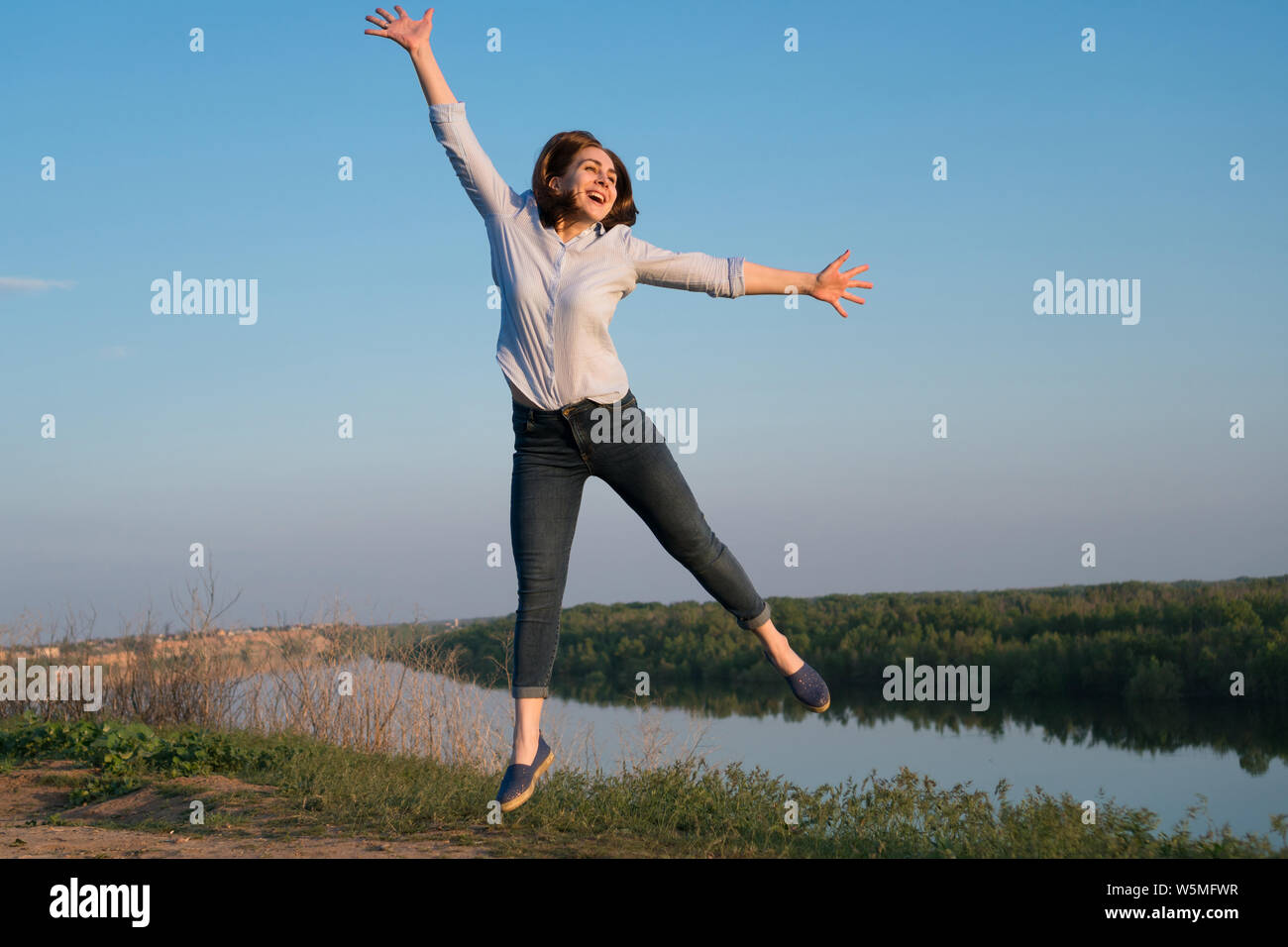 Shapely jocund girl dancing on nature background. Good-humoured lady ...