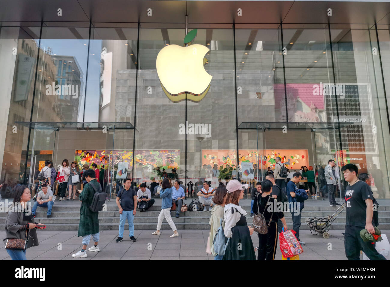 People walk past the Apple Store where the logo is partially ...