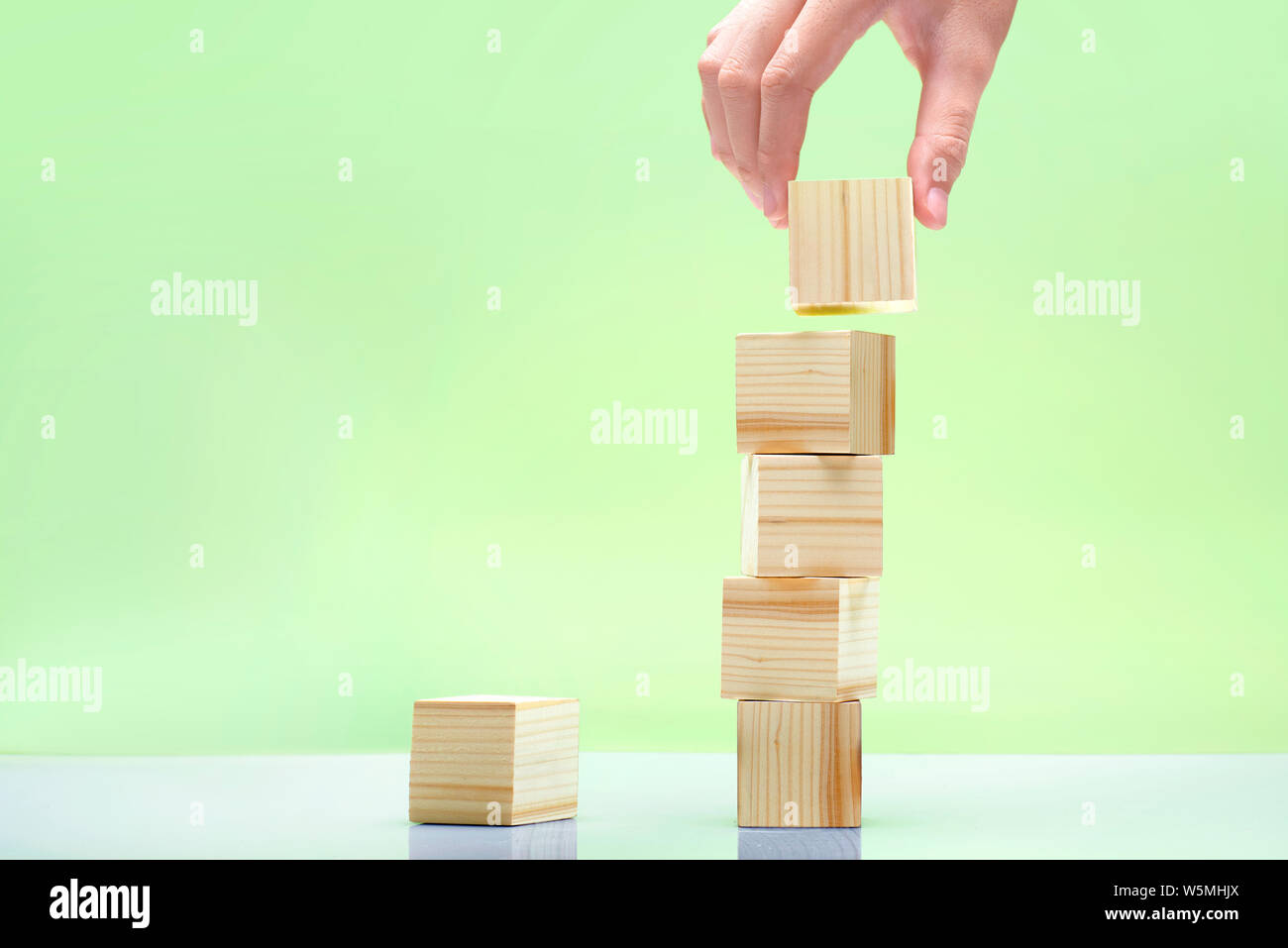Hand build a stack of wooden block toy on the table over green ...