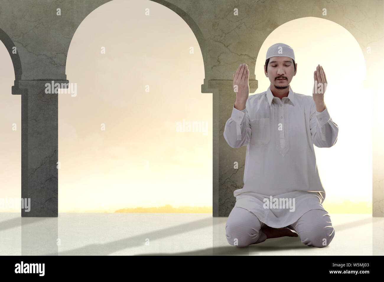 Asian Muslim man sitting in pray position while raised hands and ...
