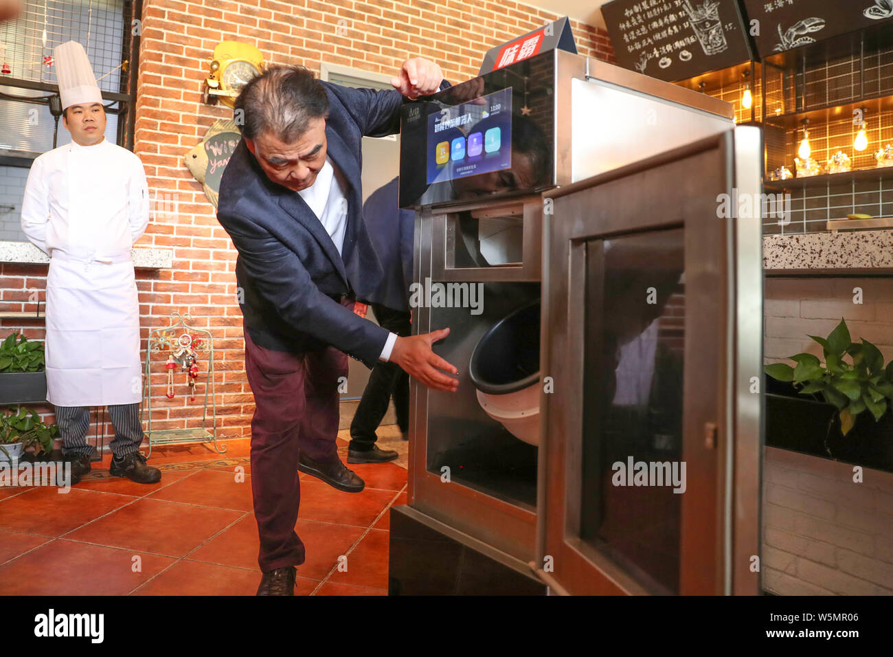 A Chinese man operates a robotic chef produced by aicanwang.com to make ...