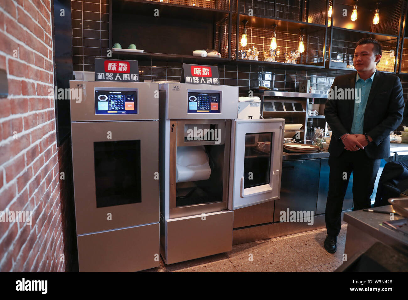A Chinese man operates a robotic chef produced by aicanwang.com to make ...