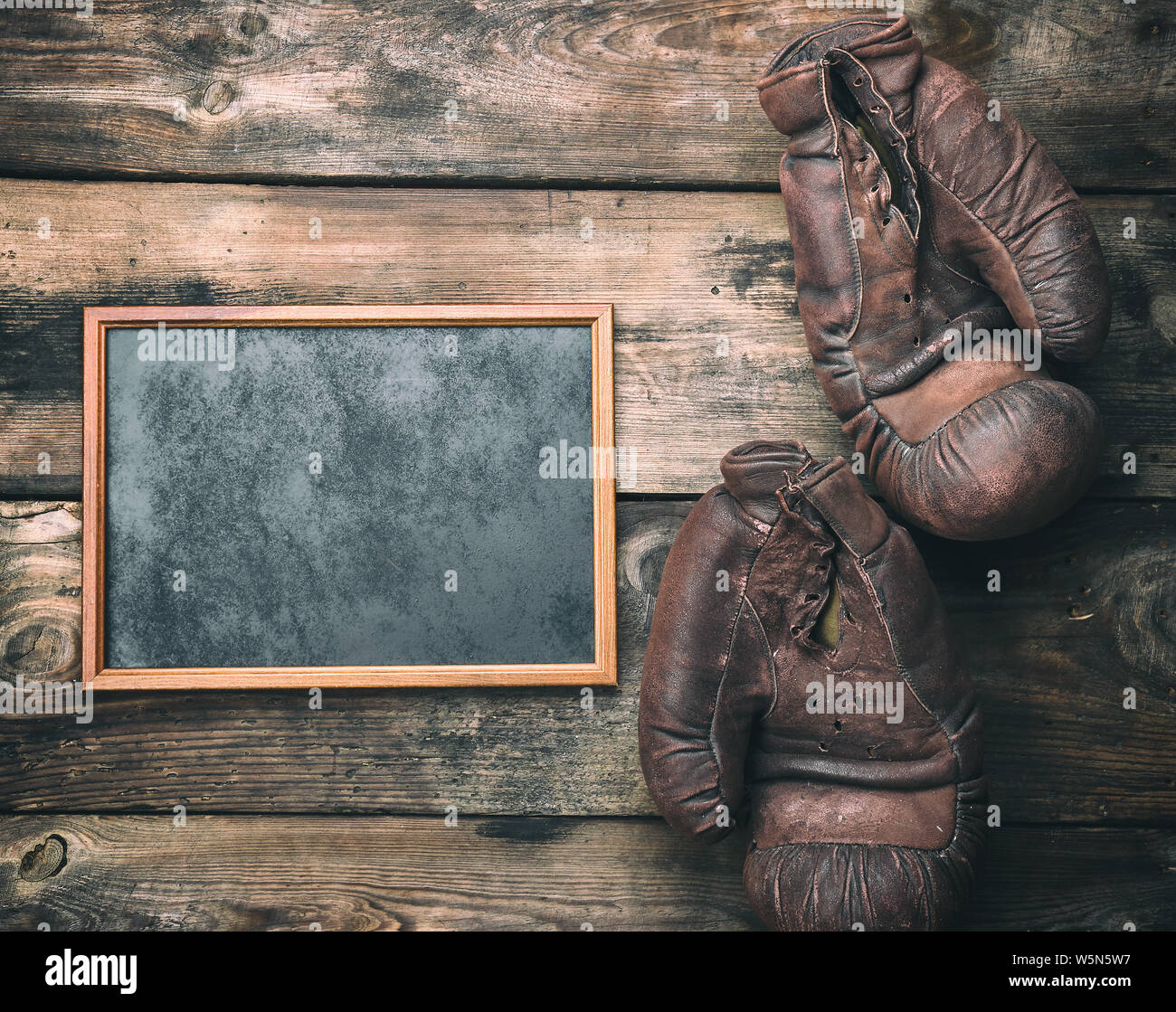 rectangular brown wooden frame and very old leather boxing gloves on a ...