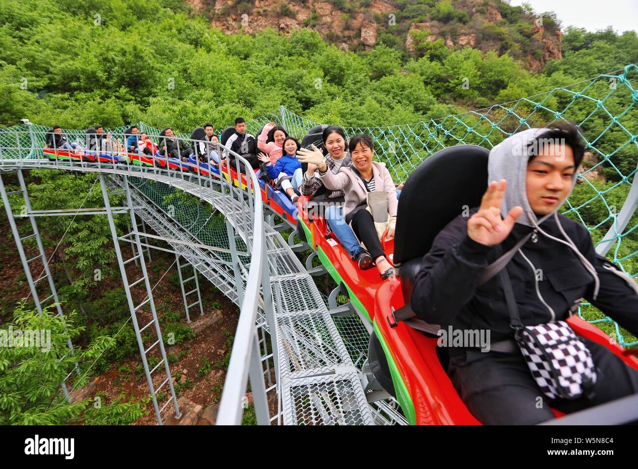 Tourists take a roller coaster ride cross over forests of the Fuxi ...