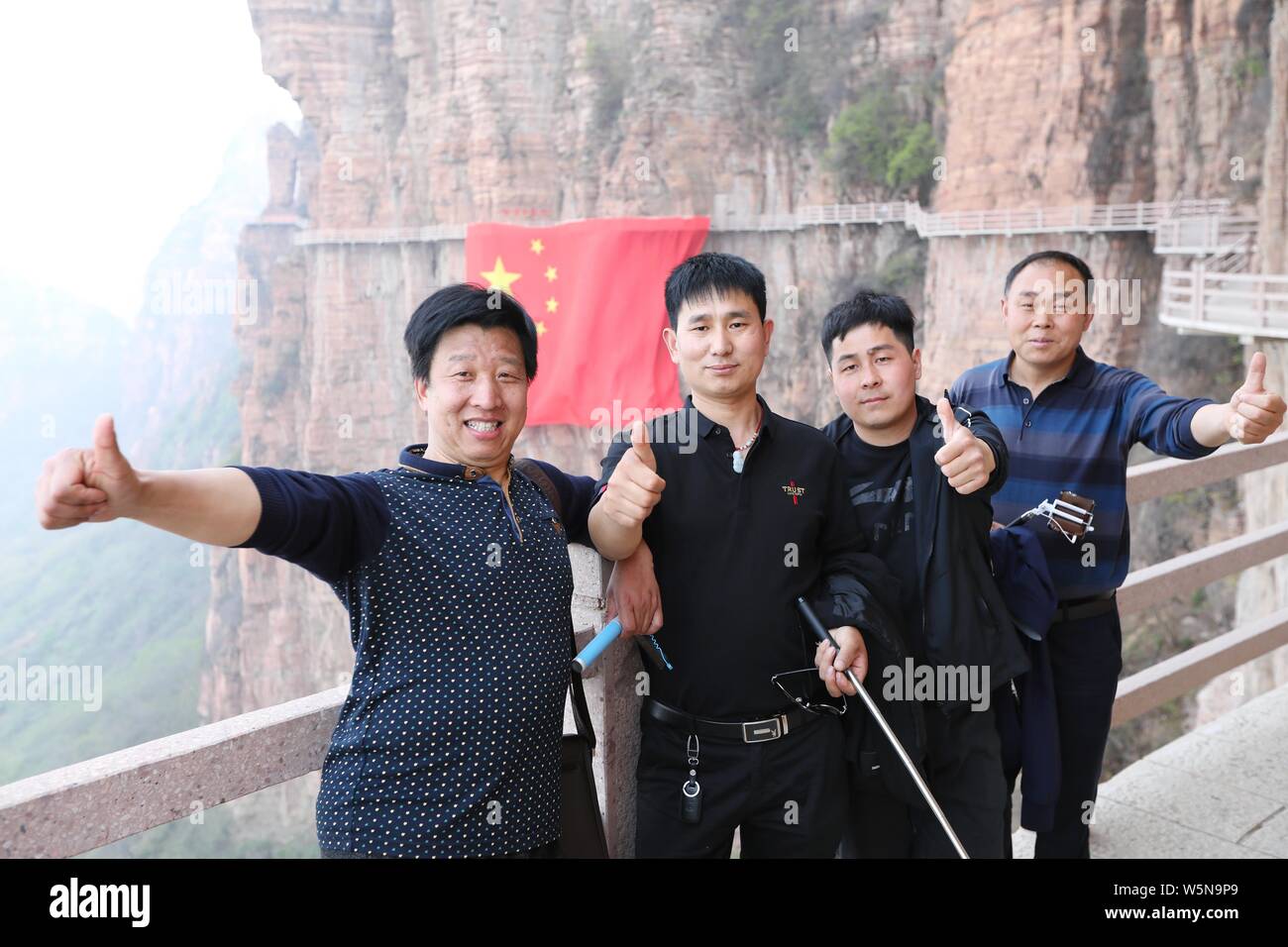 Tourists pose for photos with a huge national flag to mark the 70th ...