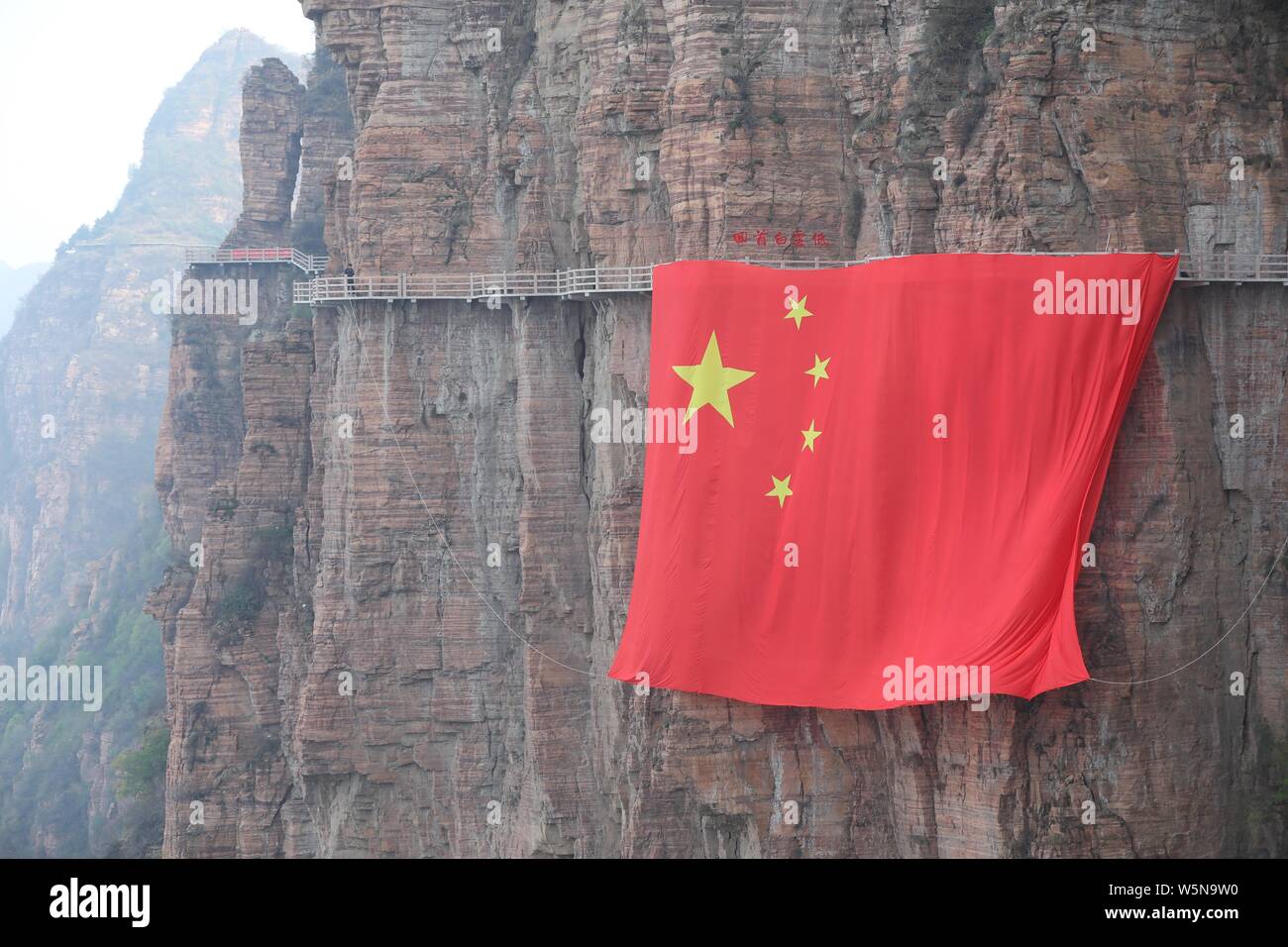 Chinese workers hang a huge national flag to mark the 70th anniversary ...