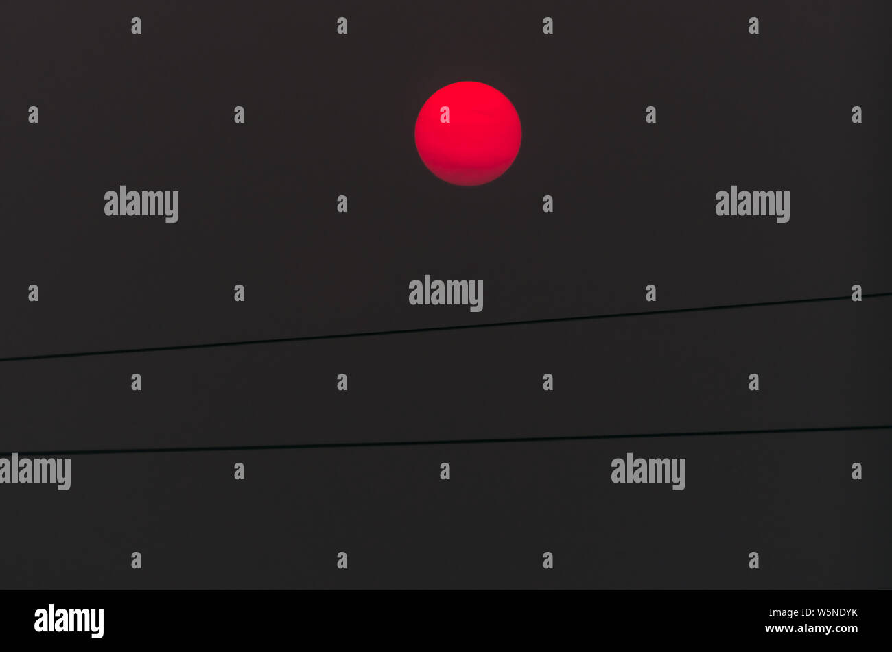Close-Up of Red Sun Circle In Hazy City Air with Two Hanging Wires ...