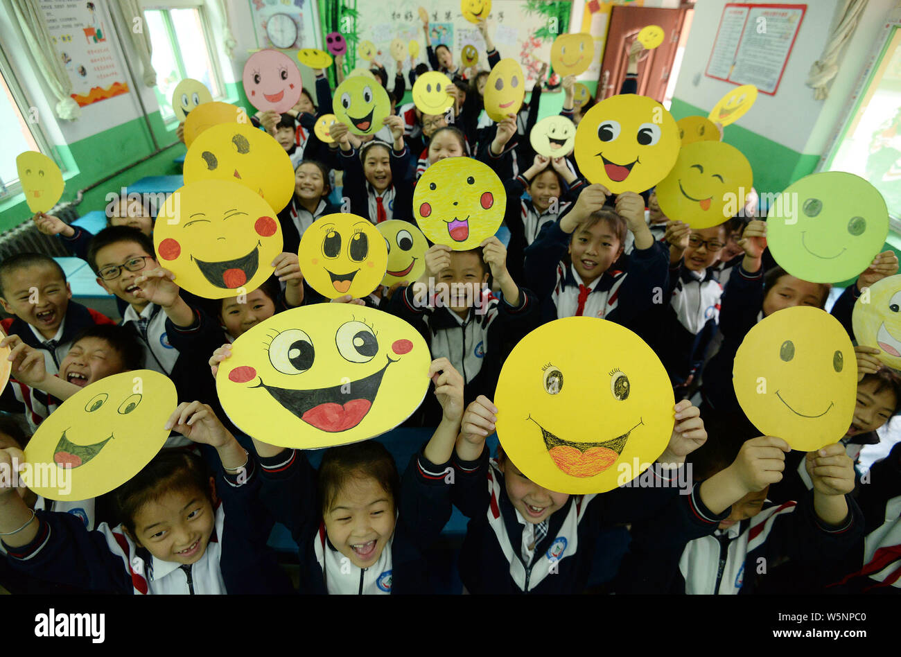 Smiley young Chinese students show smiling cartoon faces they made to ...
