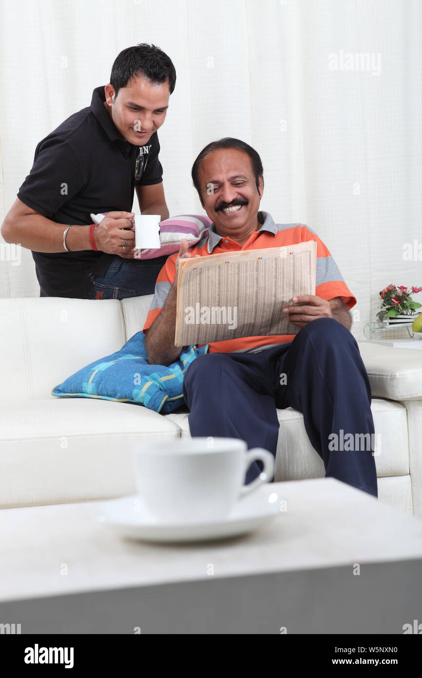 Man with his father reading newspaper and smiling Stock Photo - Alamy