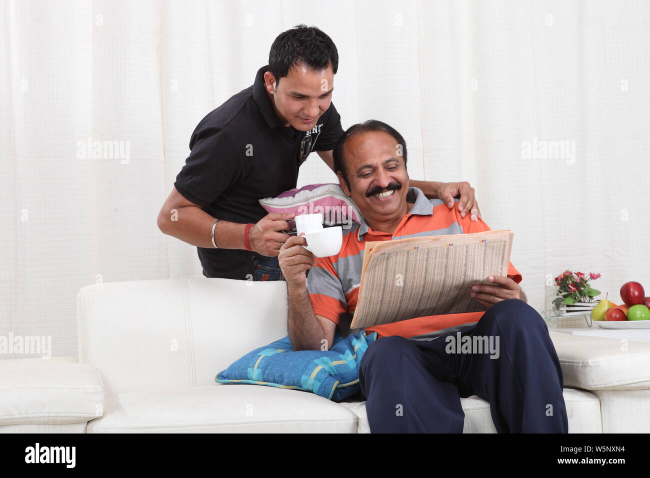 Man with his father reading newspaper and smiling Stock Photo - Alamy