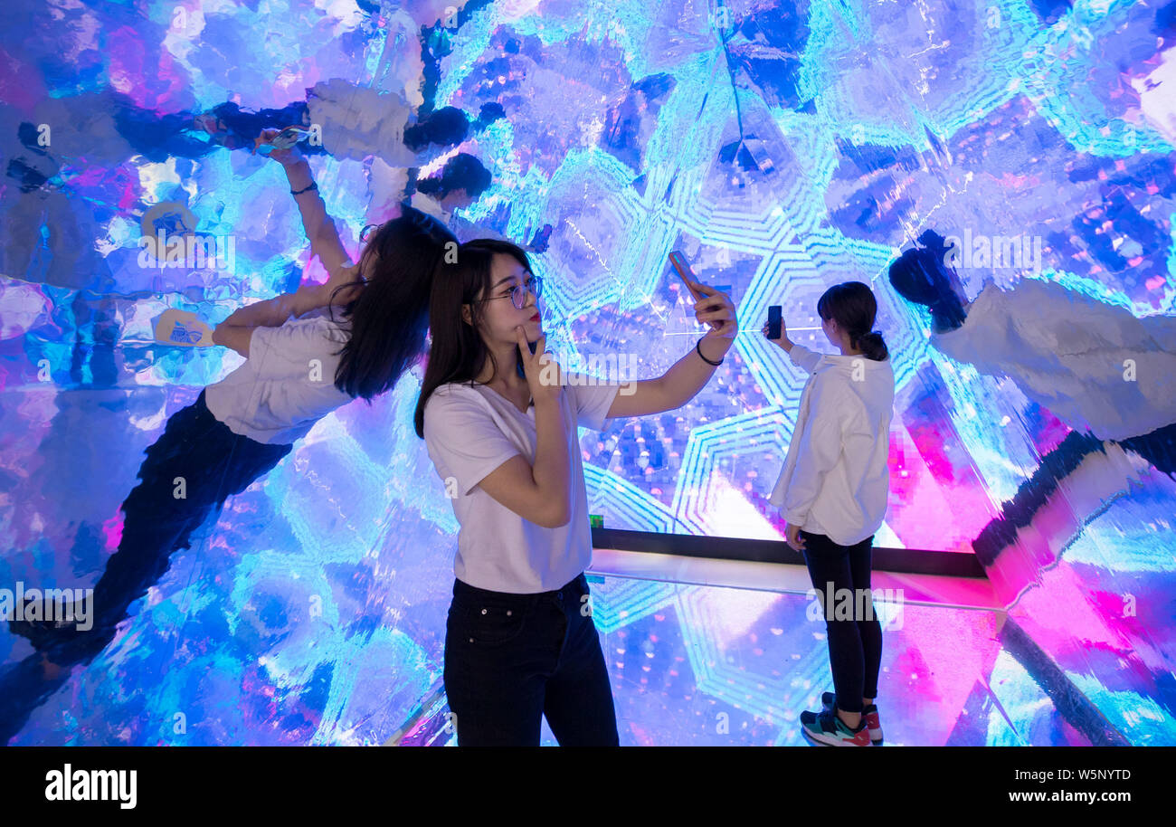 Visitors pose for photos in an image tunnel featuring theme of ...