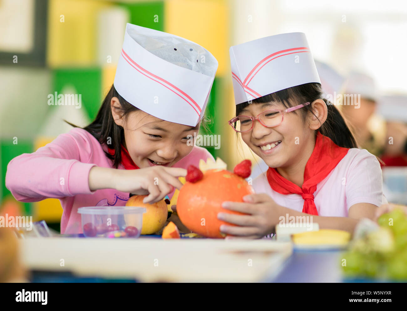 Smiley young Chinese students make smiling faces with vegetables and ...