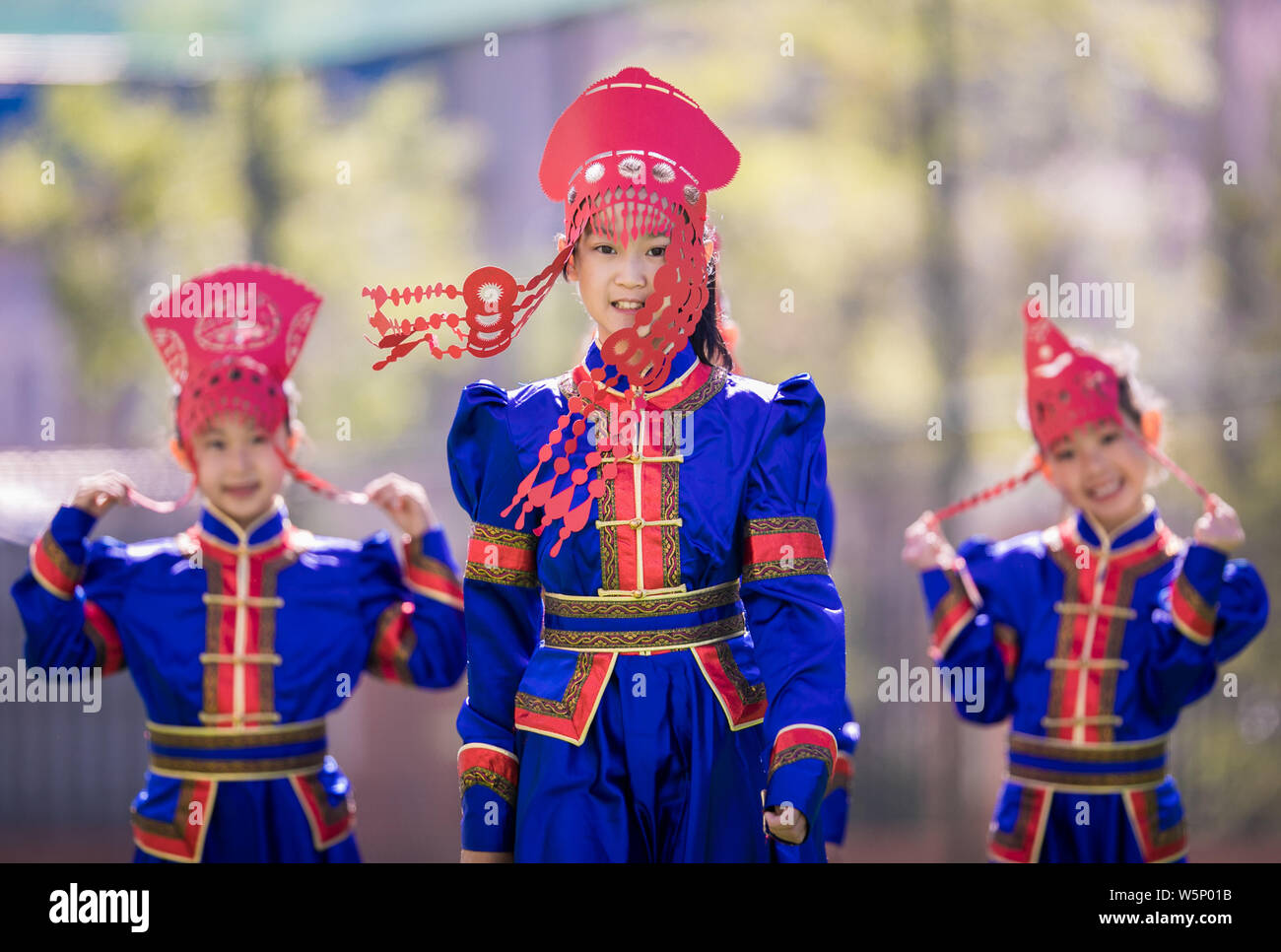 Chinese primary students dressed in traditional costumes and wearing ...