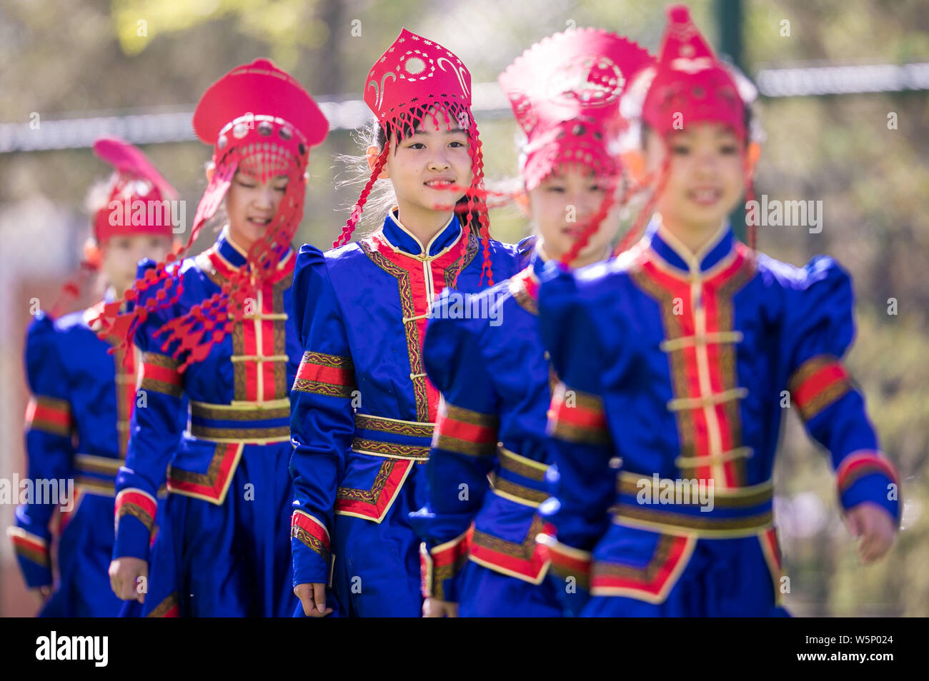Chinese primary students dressed in traditional costumes and wearing ...