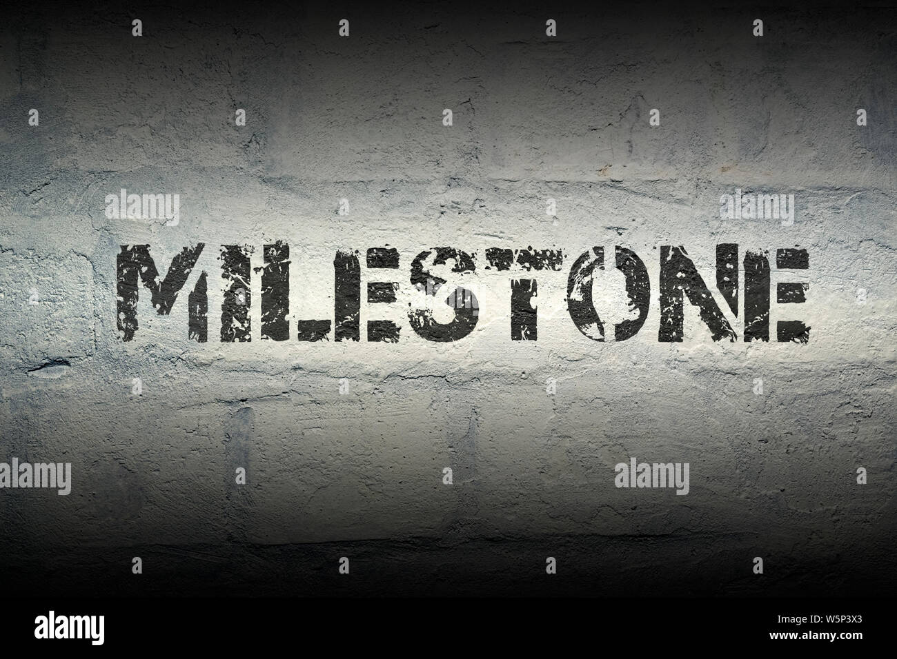 milestone stencil print on the grunge white brick wall Stock Photo - Alamy