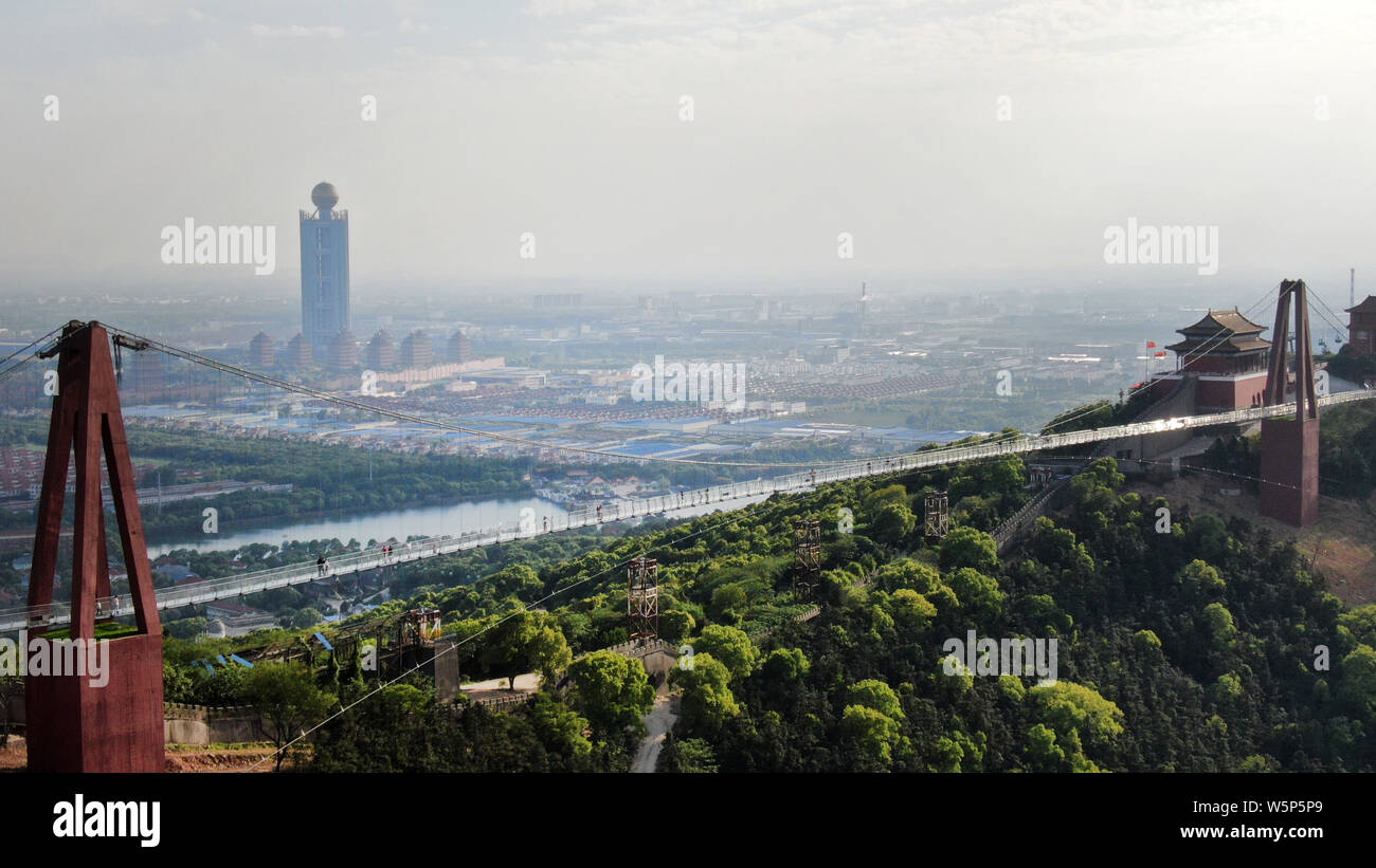 Tourists walk on the 518-meter-long glass bridge at the Huaxi World ...