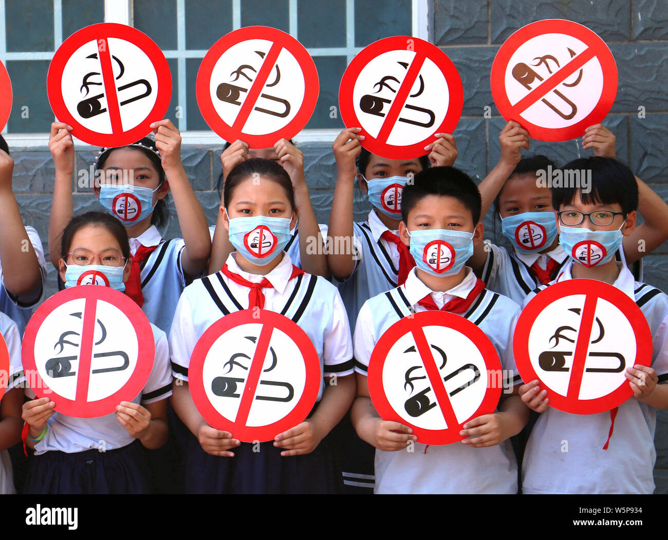 Young Chinese pupils wearing face masks show No Smoking signs to ...