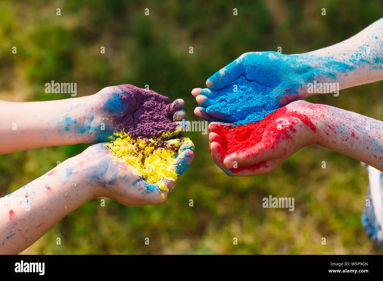 Hands Palms of young people covered in purple, yellow, red, blue Holi ...