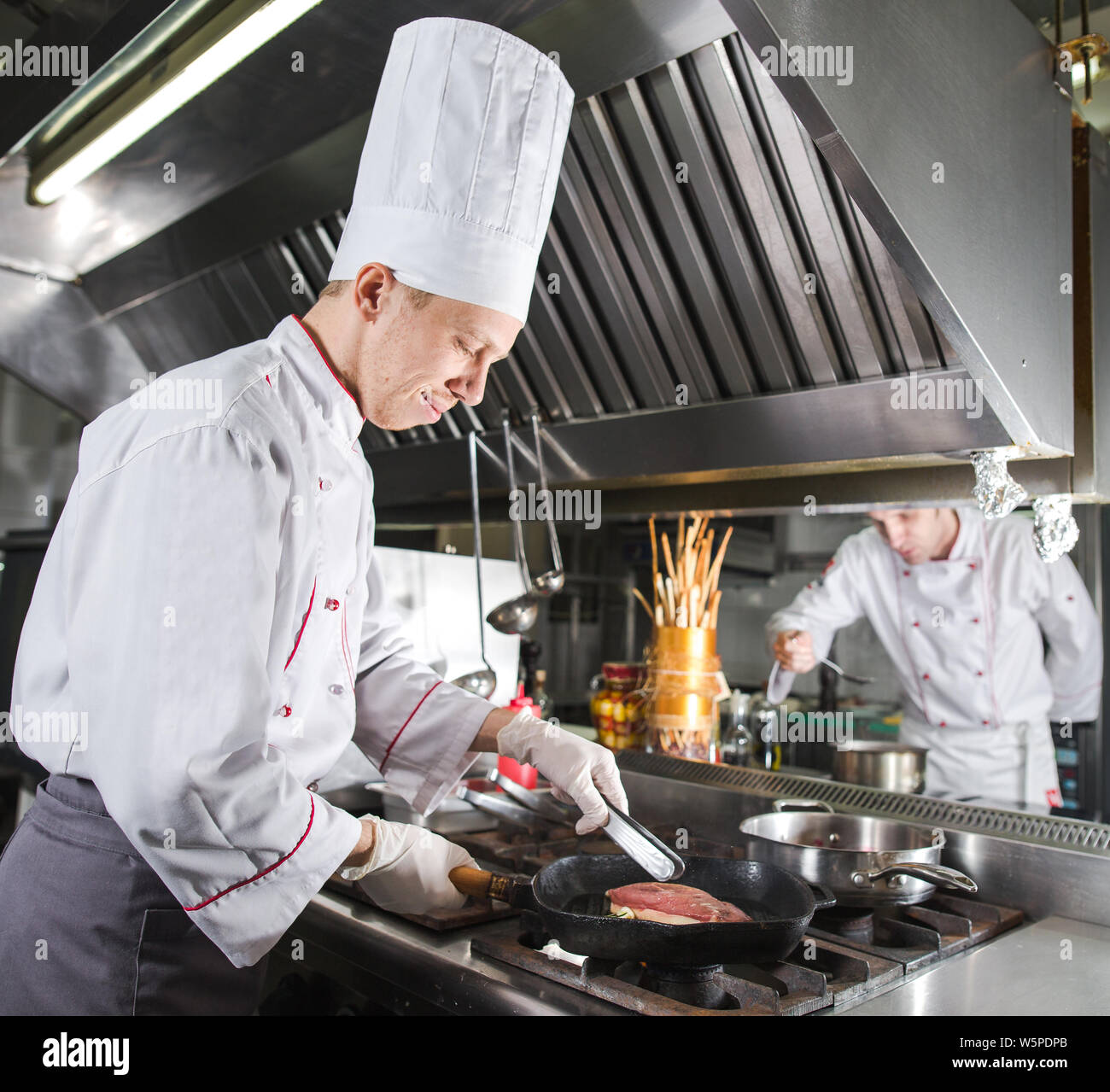 Chef in restaurant kitchen at stove with pan, cooking Stock Photo - Alamy
