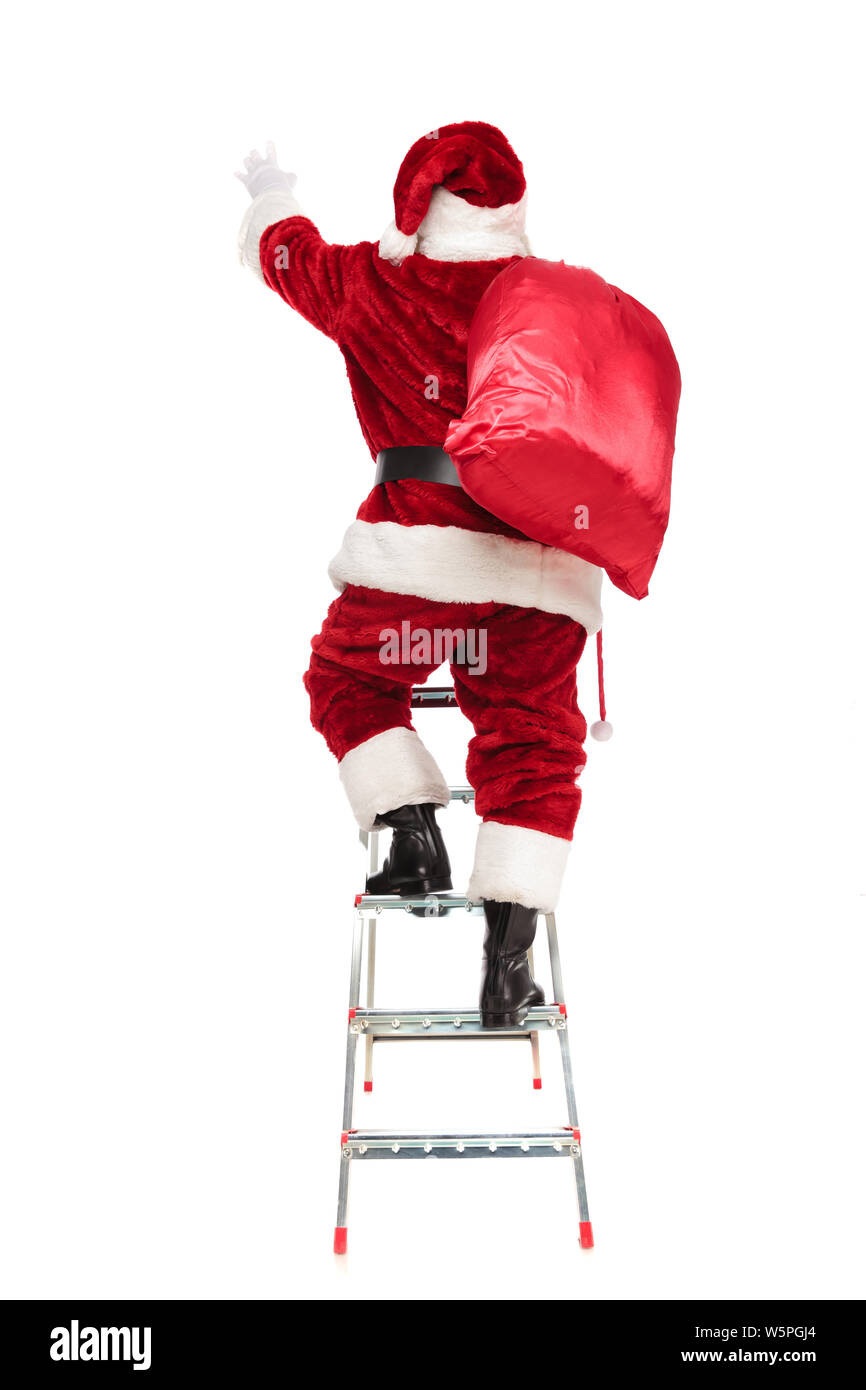 back view of santa stretching hand while climbing the ladder and ...